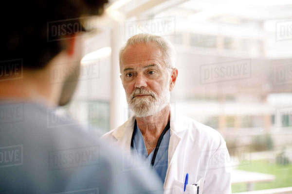Contemplating wrinkled nurse talking to male colleague in hospital ...