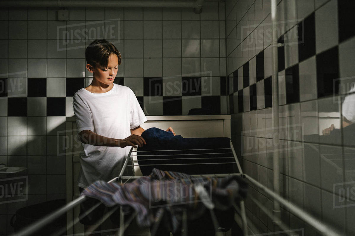Boy doing laundry in utility room - Stock Photo - Dissolve