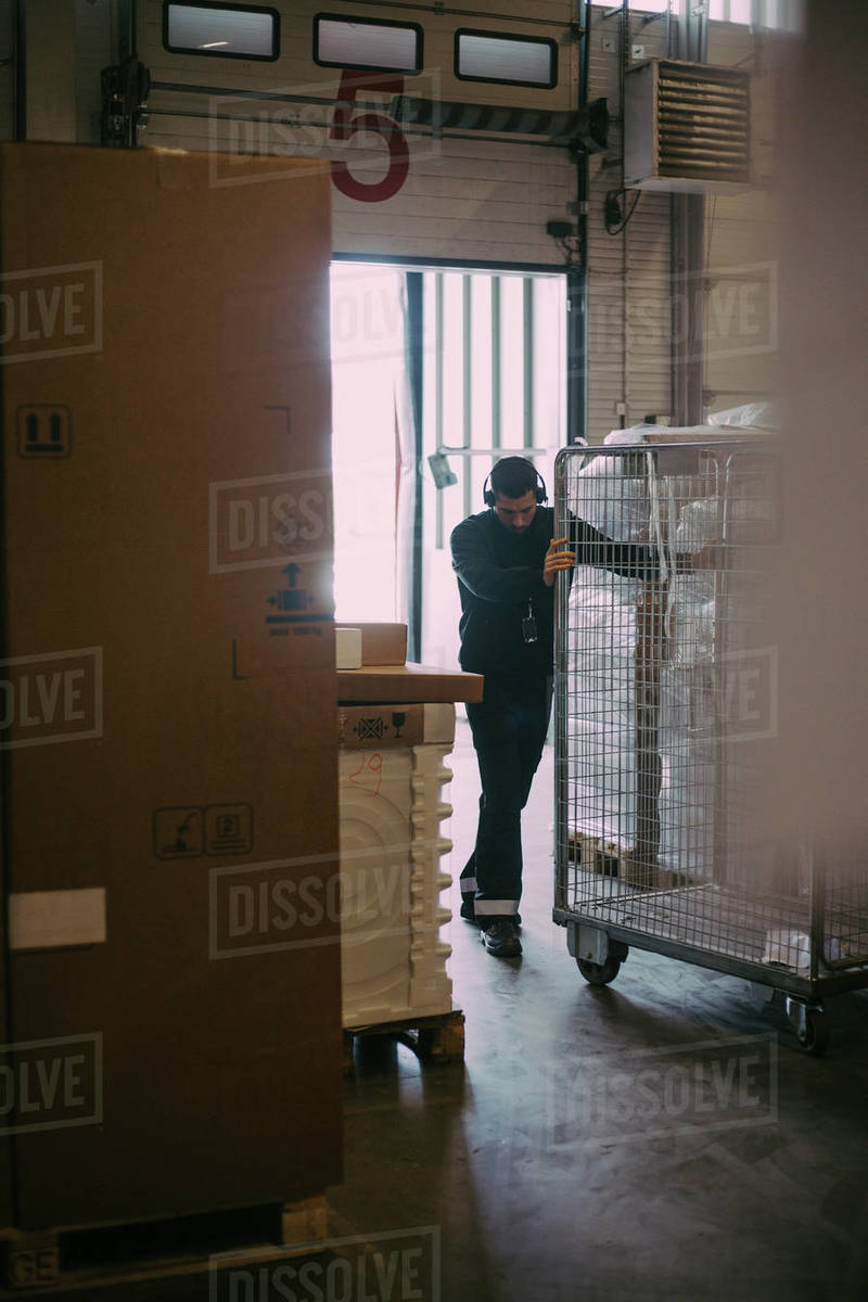 Male manual worker pushing cage trolley at warehouse - Royalty-free ...