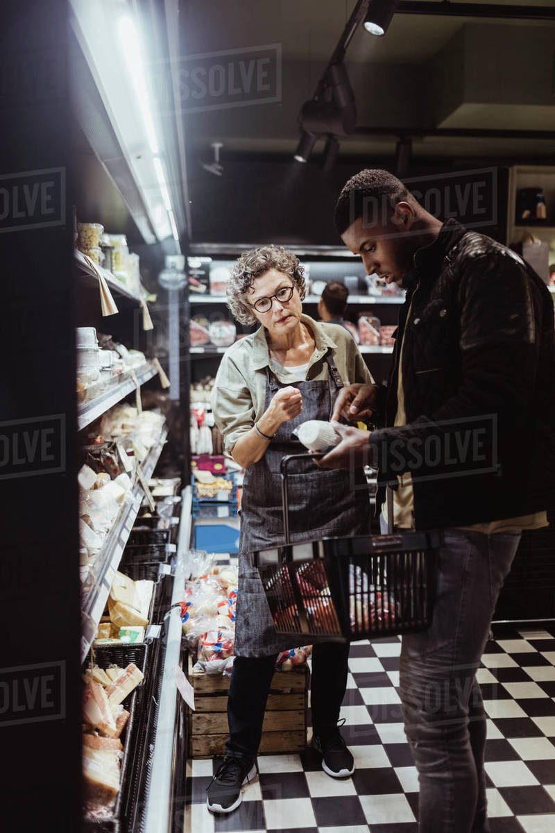 Male customer looking at package product while female owner standing by ...