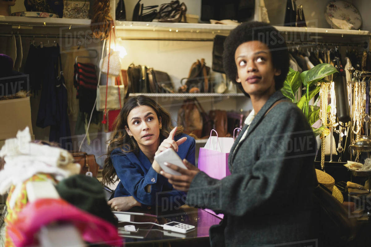 Female customer looking up while owner talking to her in boutique ...