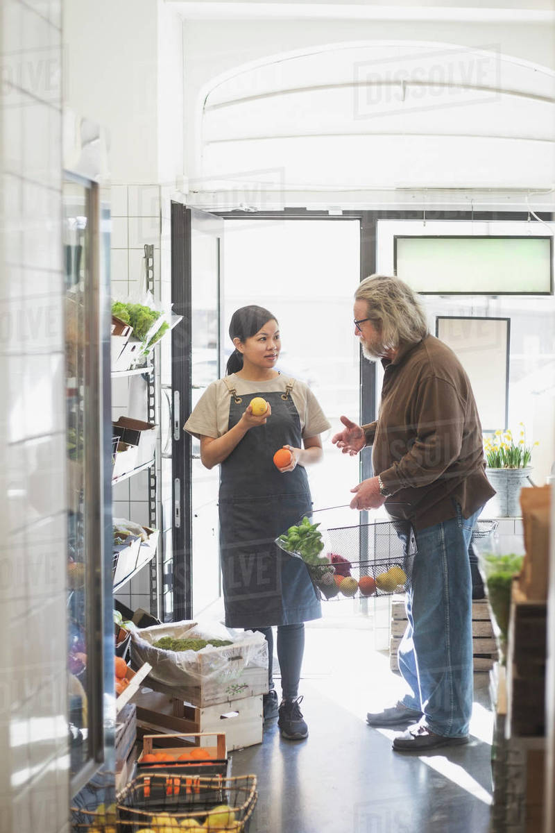 Senior male customer talking with female owner while buying food in ...