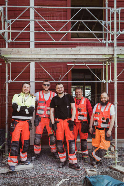 Full length of male construction workers standing together at site ...