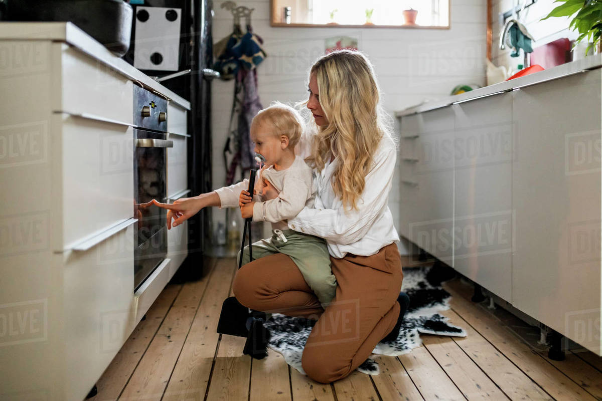 Woman showing oven to son in kitchen at home - Royalty-free Stock Photo ...