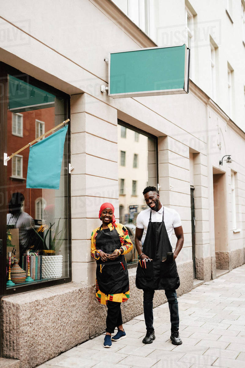 Happy male and female coworkers standing outside barber shop - Stock ...