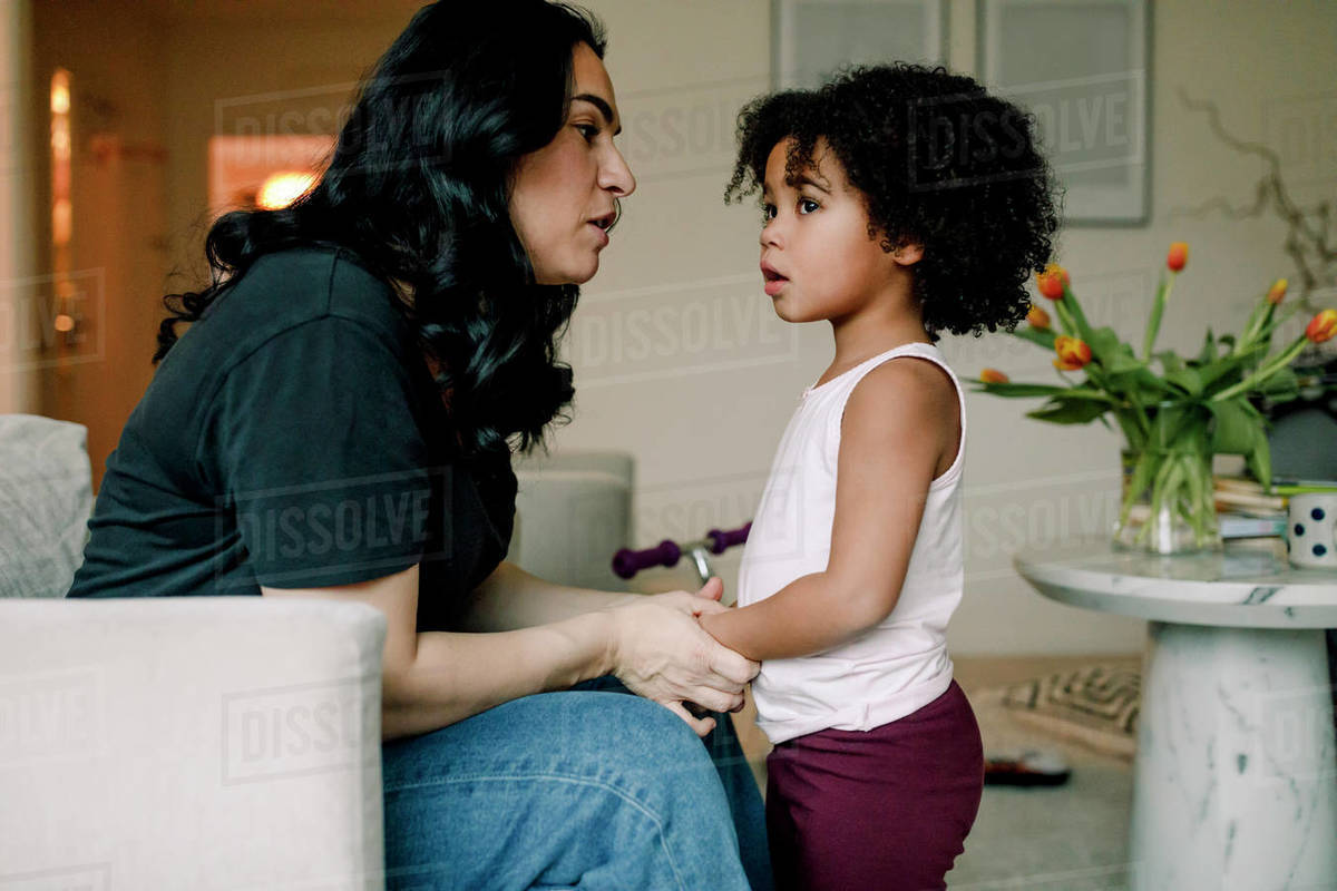 Mother talking with daughter in living room at home - Royalty-free ...
