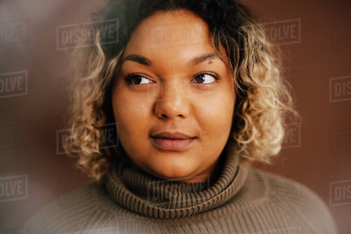 Contemplative woman over brown background in studio - Royalty-free ...