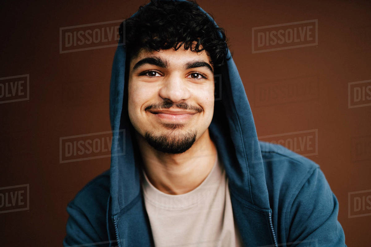 Portrait of smiling man wearing jacket against brown background ...