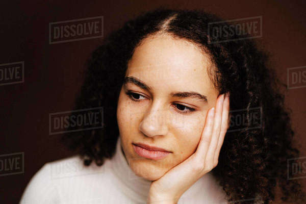 Contemplative woman over brown background - Stock Photo - Dissolve