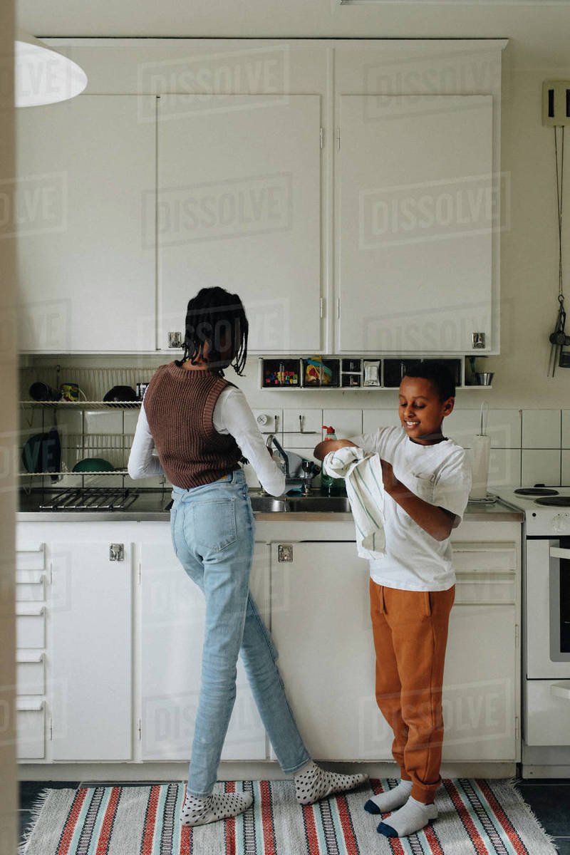 Brother and sister cleaning kitchen utensils at home - Royalty-free ...