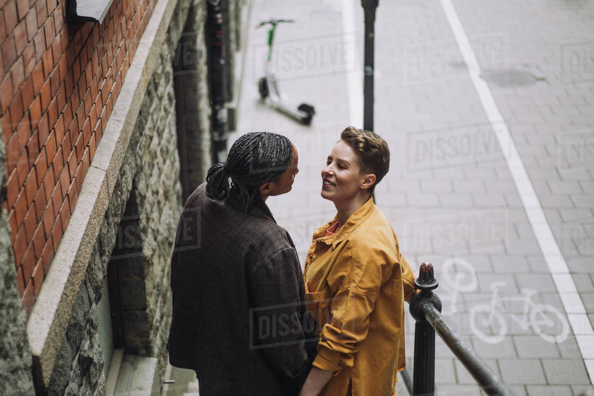 Smiling mid adult woman talking with girlfriend while standing by ...