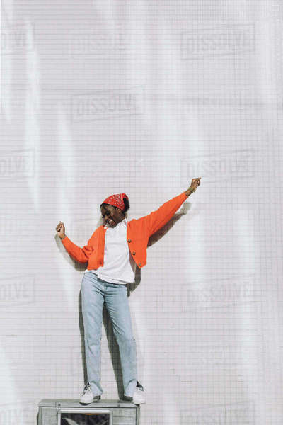 Full length of young woman dancing with hand raised while standing ...