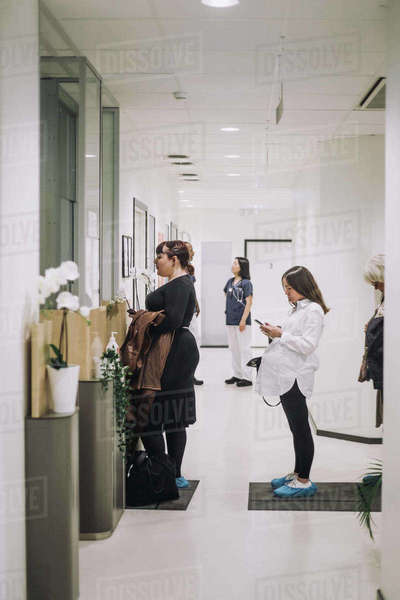 Full length side view of female patients waiting in line at hospital ...