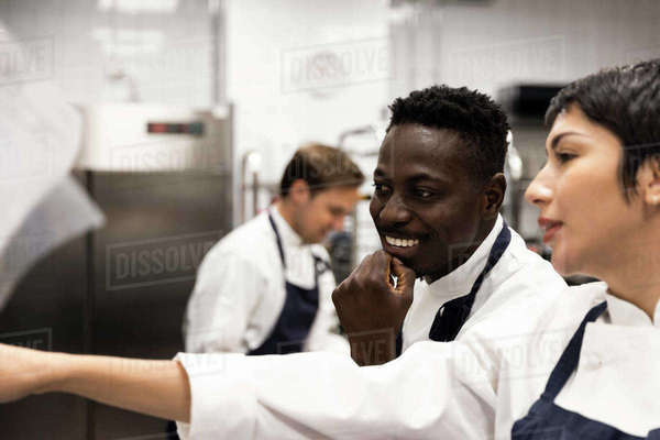 Smiling male and female colleagues having discussion in kitchen of ...