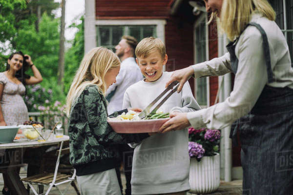 Happy siblings looking at food during dinner party - Stock Photo - Dissolve