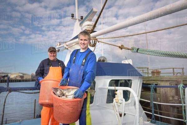 Fishermen with catch of fish on deck of trawler, portrait - Stock Photo ...