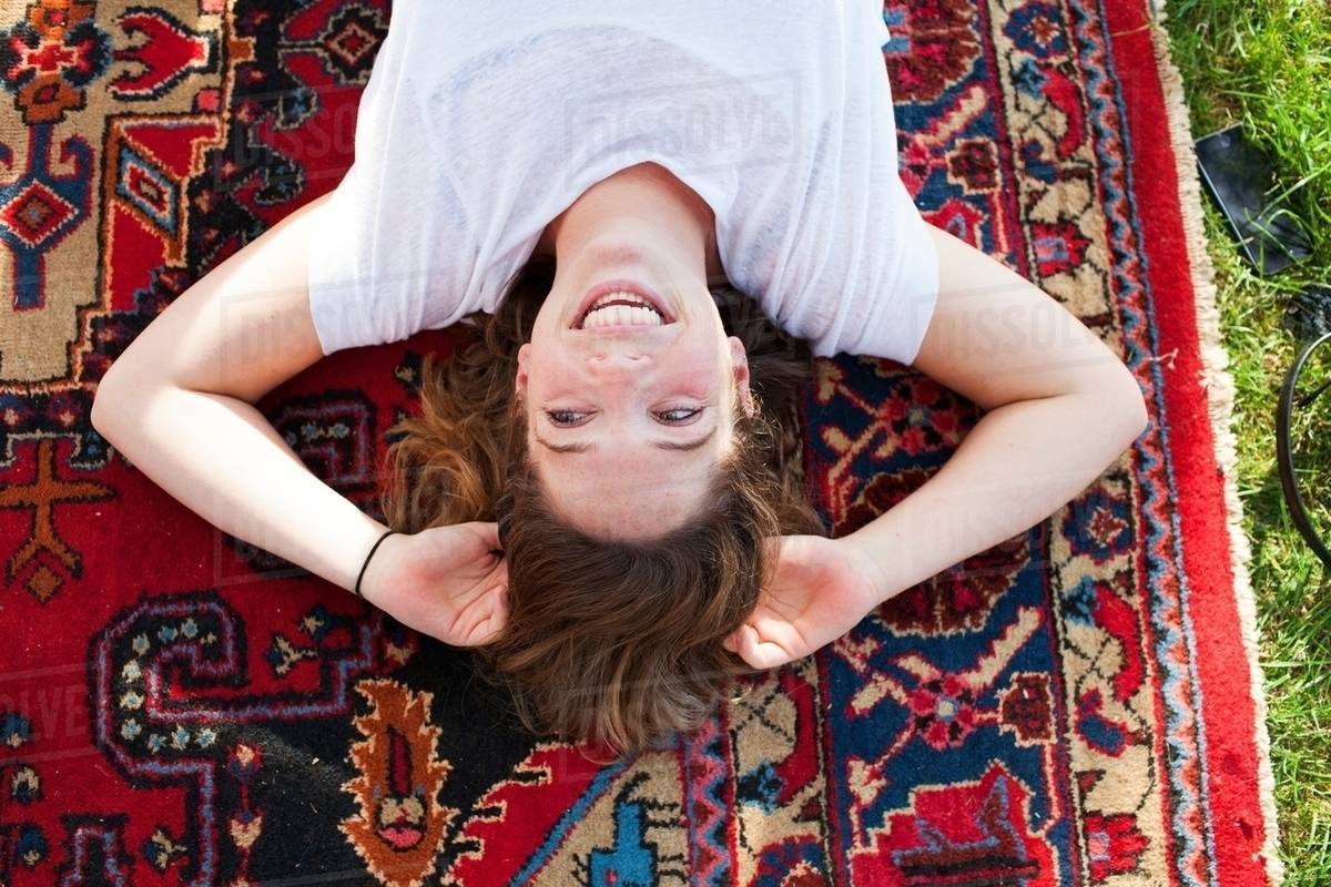 Overhead view of young woman lying back on rug - Stock Photo - Dissolve