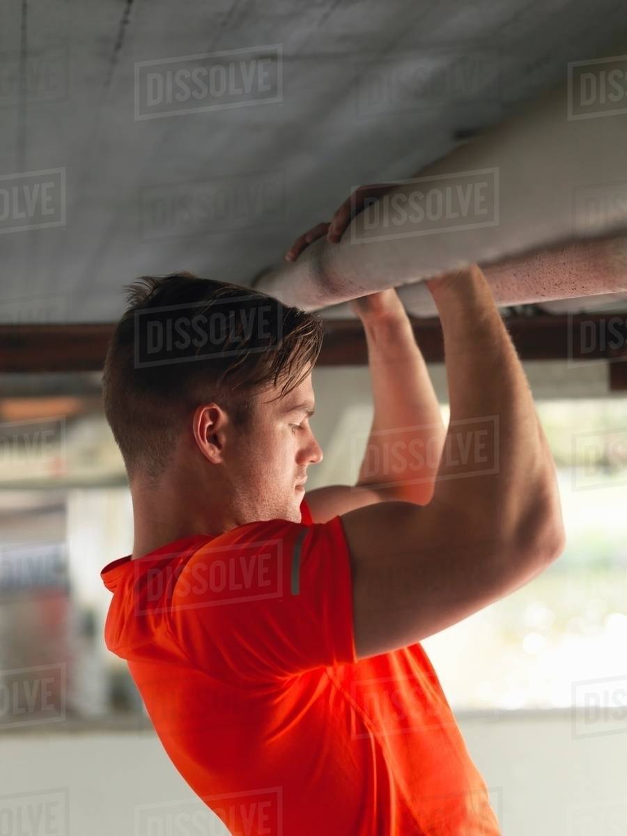 Young man doing pull ups under bridge - Stock Photo - Dissolve