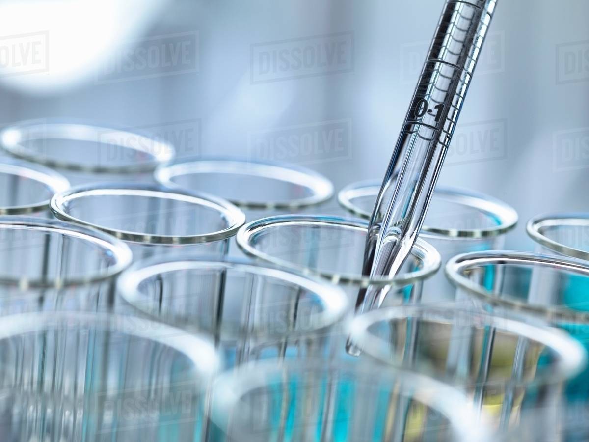 Cropped view of graduated pipette pipetting liquid into test tubes ...