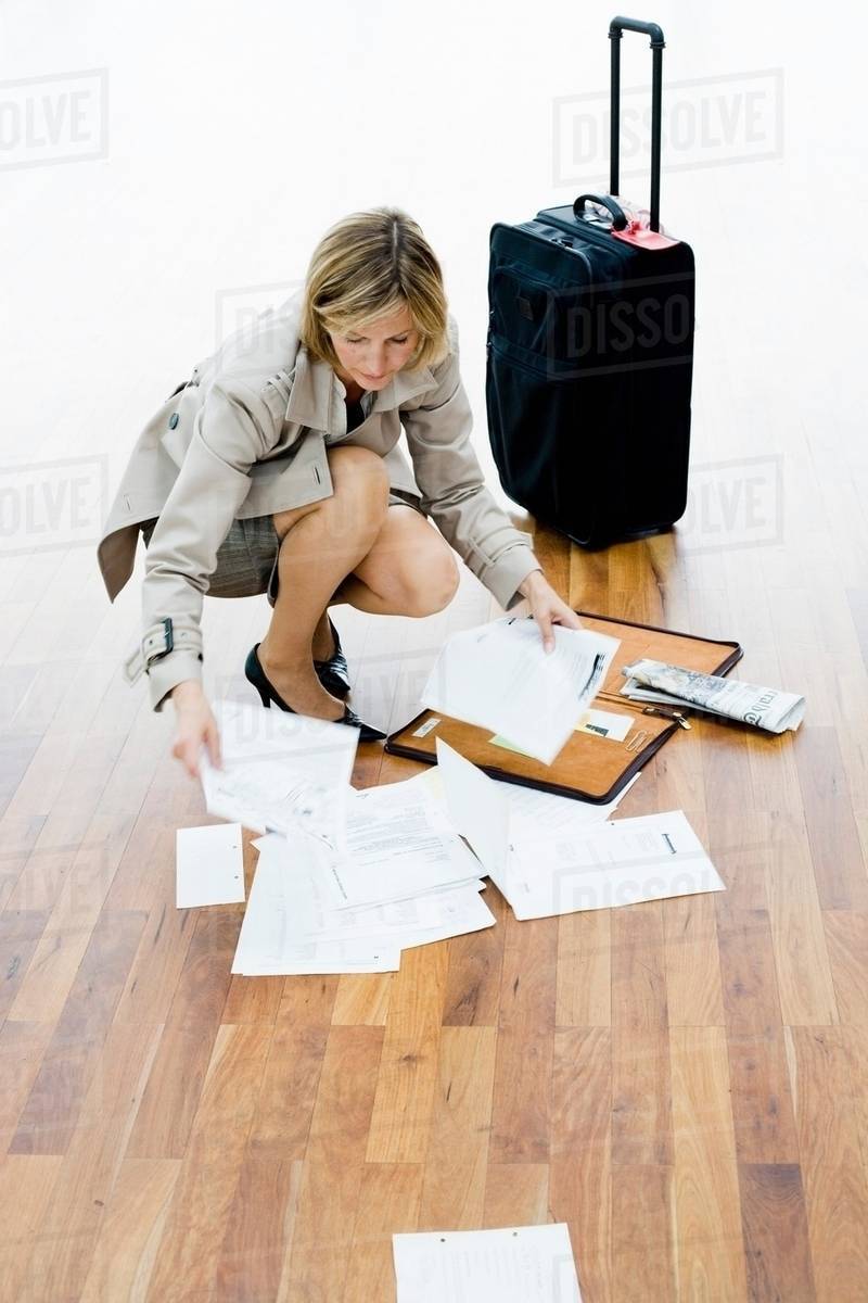 Woman sorting papers spread on floor - Stock Photo - Dissolve