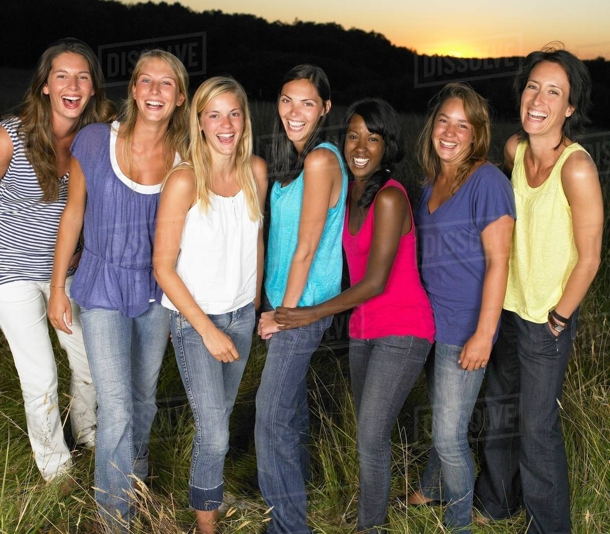 Group of girlfriends laughing in a field - Stock Photo - Dissolve