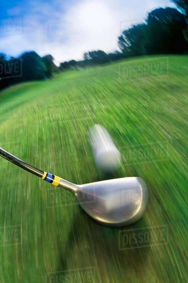Golf club hitting ball on golf course - Stock Photo - Dissolve