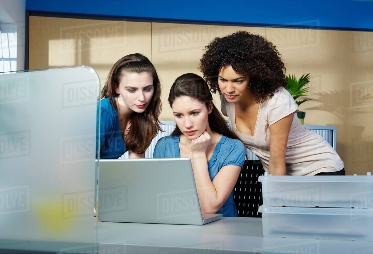 Group of young women with laptop at desk - Stock Photo - Dissolve