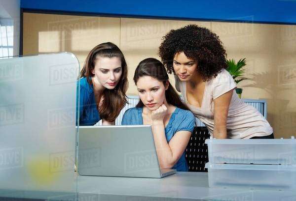 Group of young women with laptop at desk - Stock Photo - Dissolve
