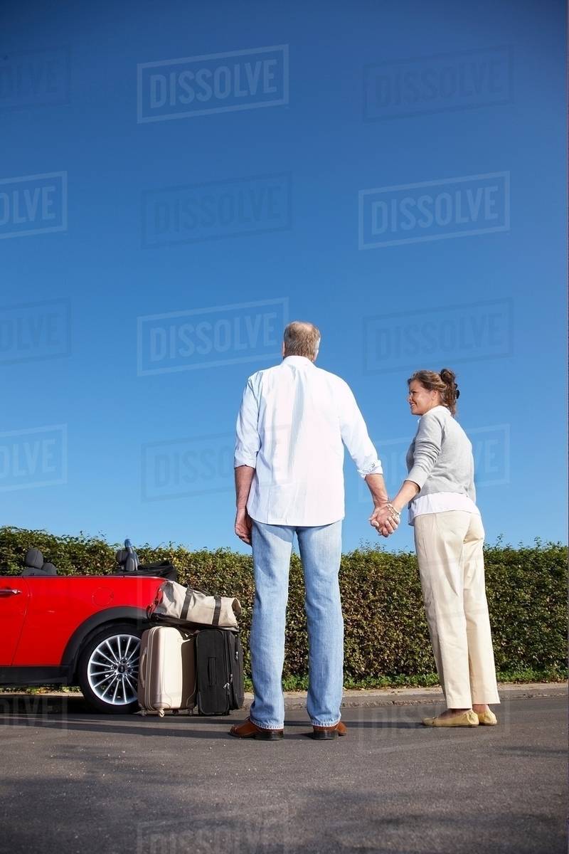Couple holding hands by car - Stock Photo - Dissolve