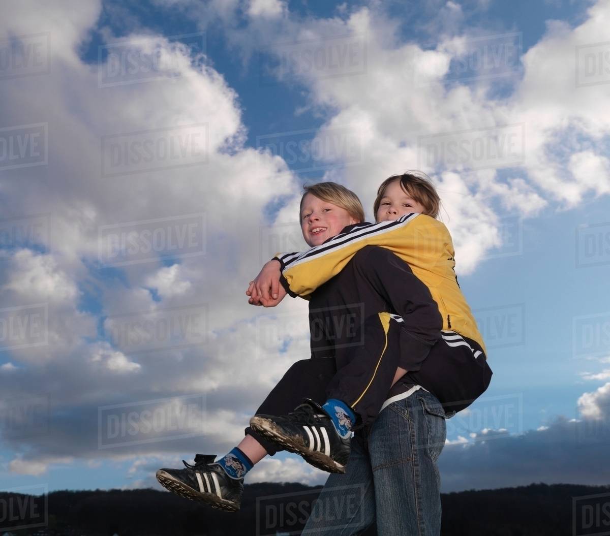 Boy carrying girl piggyback style - Royalty-free Stock Photo | Dissolve