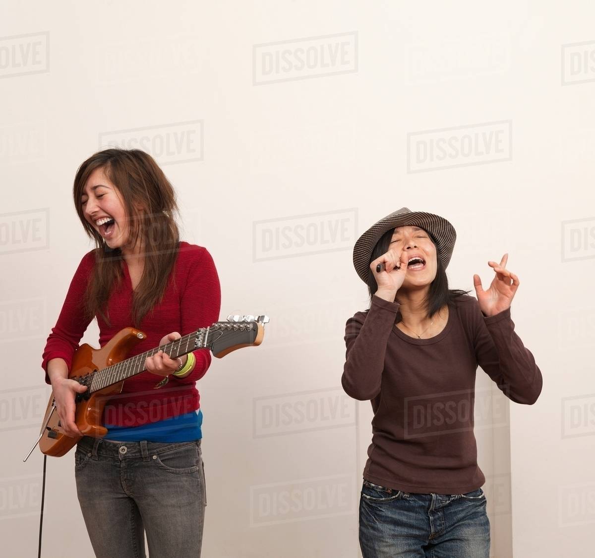 Two women singing and playing guitar - Royalty-free Stock Photo | Dissolve