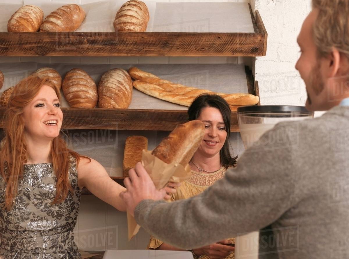 Woman handing bread to customer - Royalty-free Stock Photo | Dissolve