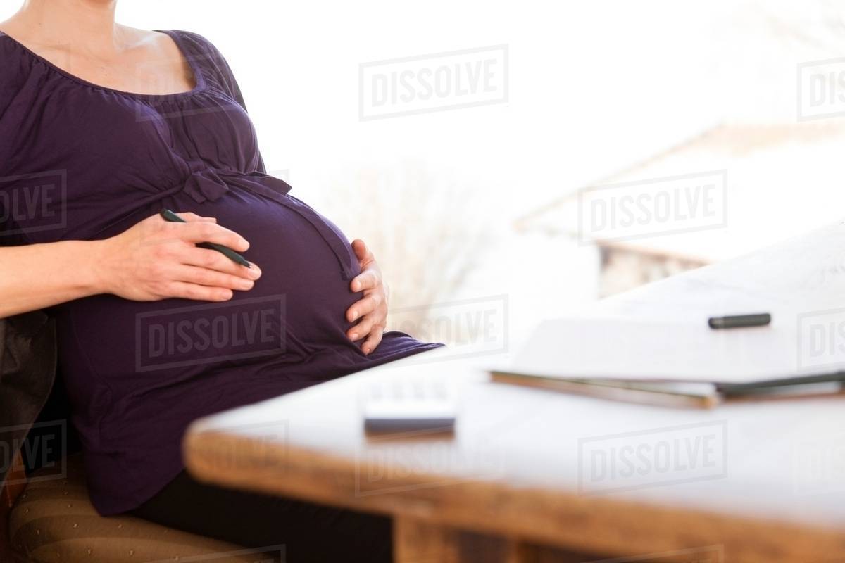 Pregnant woman working in home office - Stock Photo - Dissolve