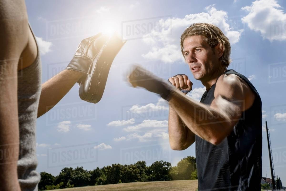 Male boxer training with personal trainer in park - Stock Photo - Dissolve
