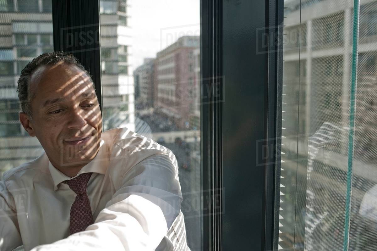 Man leaning at window smiling - Stock Photo - Dissolve