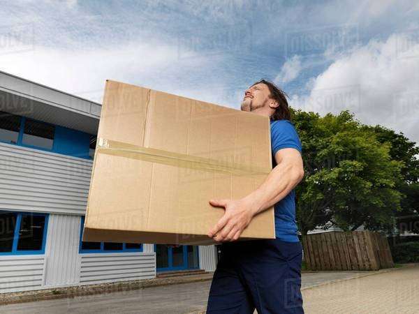 Man carrying heavy box - Royalty-free Stock Photo | Dissolve