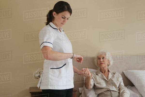 Nurse taking pulse of elderly woman - Stock Photo - Dissolve