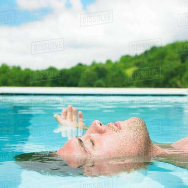 Young man floating in water - Stock Photo - Dissolve