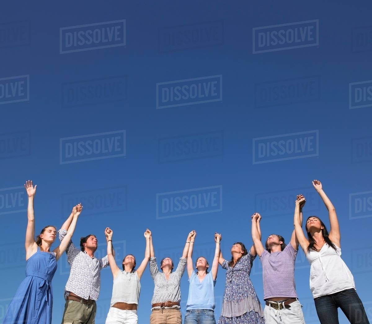 Group of young people raising arms - Stock Photo - Dissolve