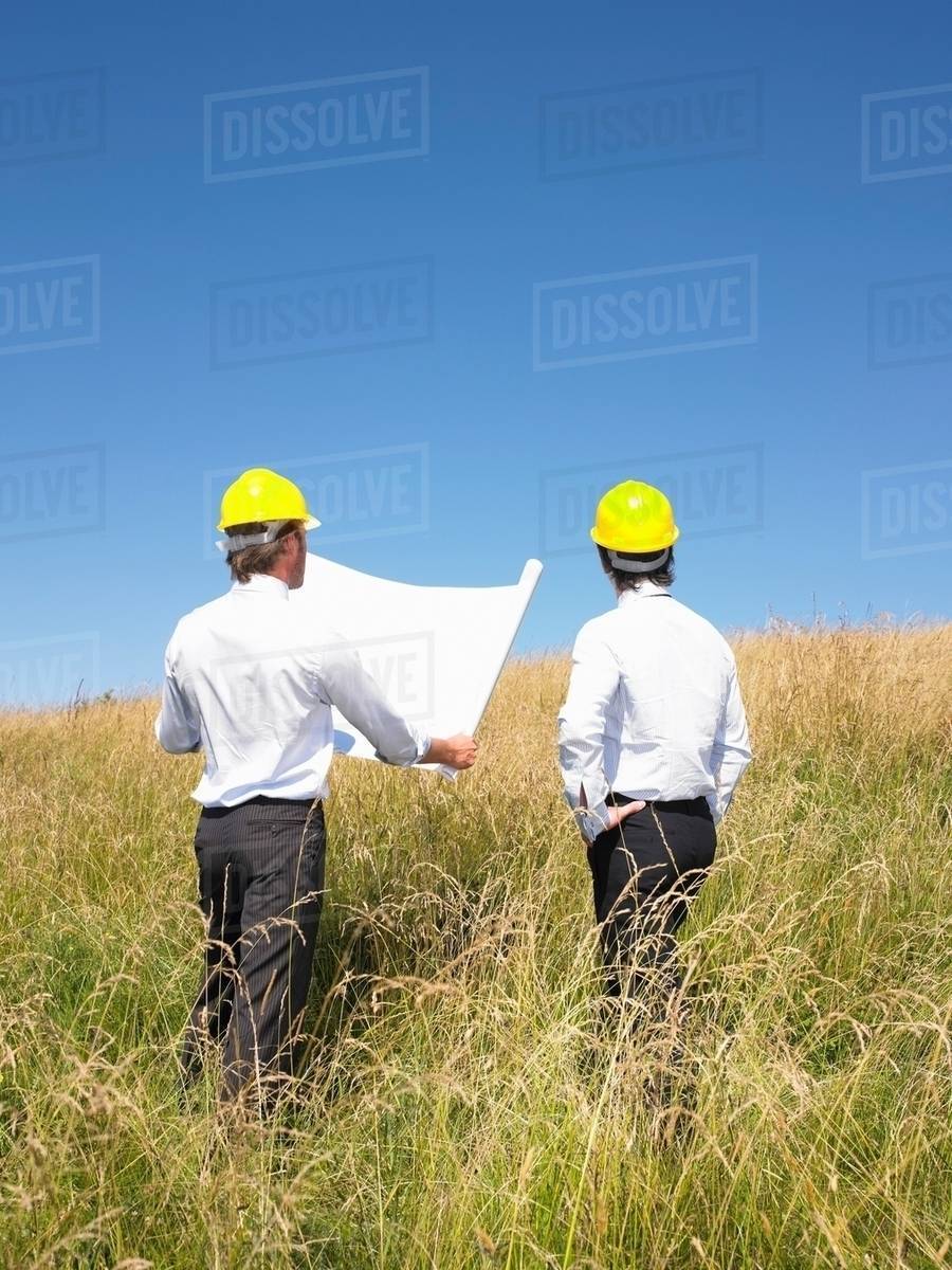 Contractors with blueprints in field - Royalty-free Stock Photo | Dissolve