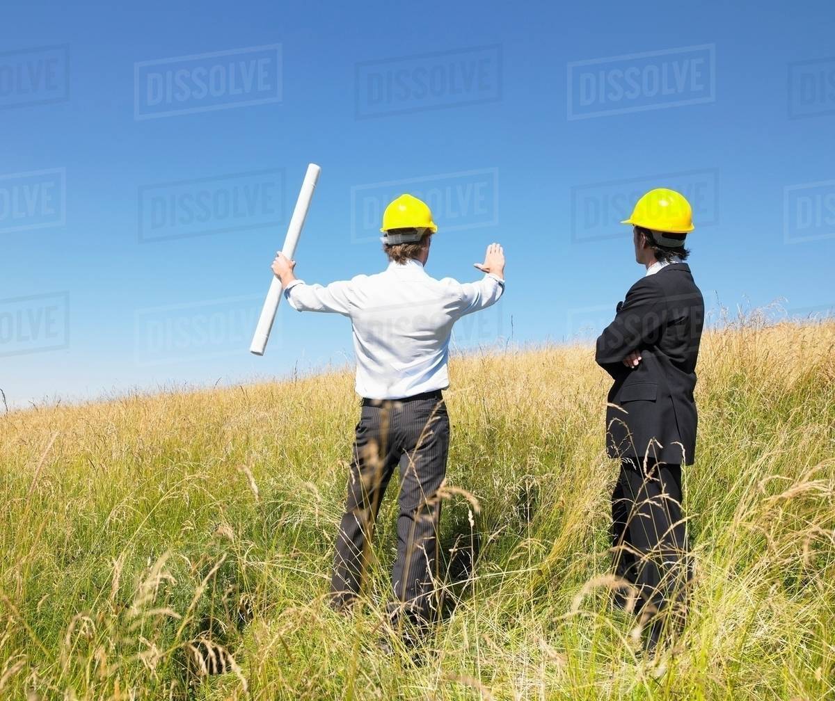 Contractors with blueprints in field - Royalty-free Stock Photo | Dissolve