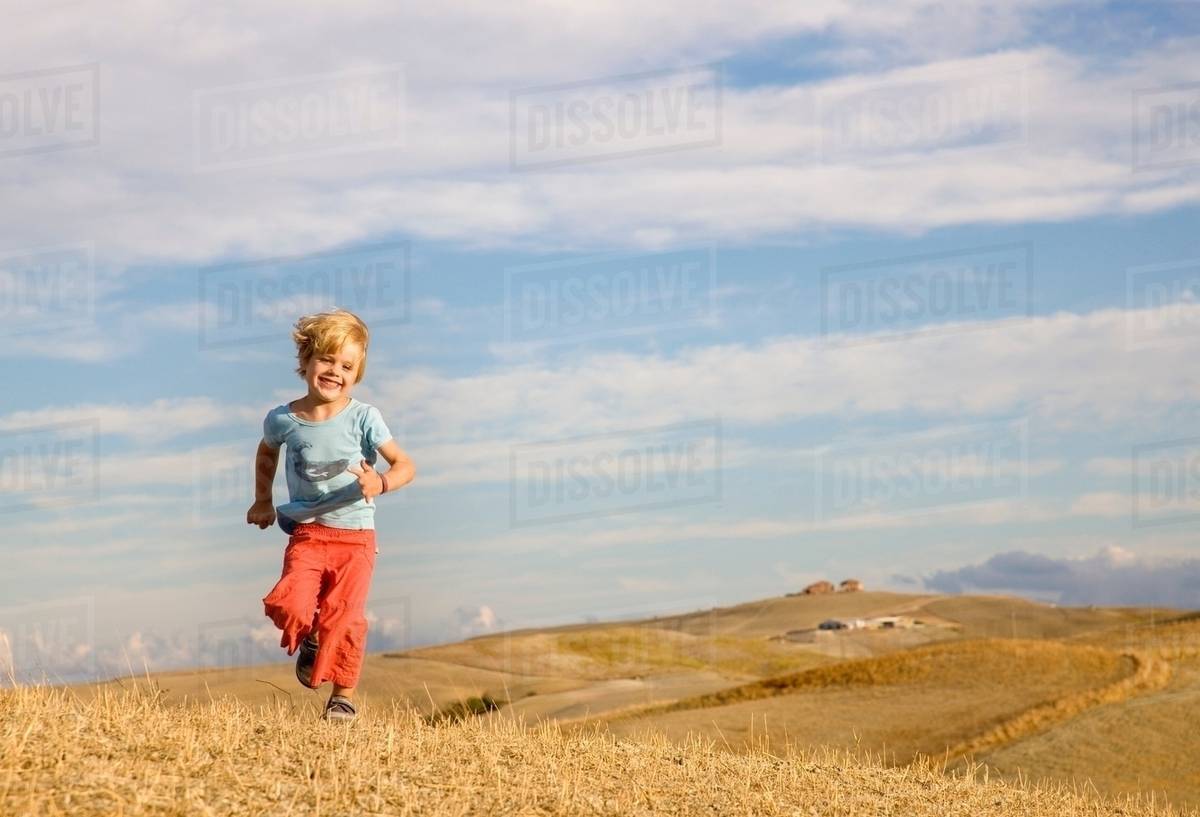 Boy running across field - Royalty-free Stock Photo | Dissolve