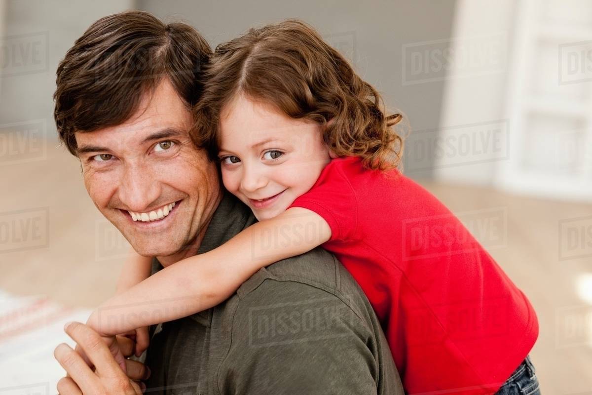 Daughter riding on father's back - Stock Photo - Dissolve