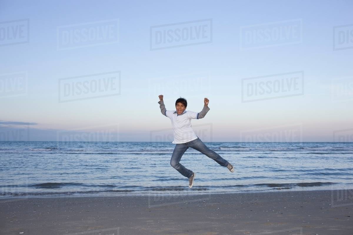 Boy jumping on the beach. - Royalty-free Stock Photo | Dissolve
