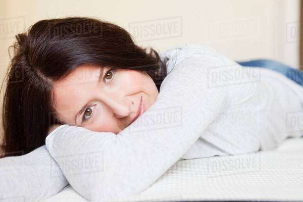 Woman resting on bed smiling - Royalty-free Stock Photo | Dissolve