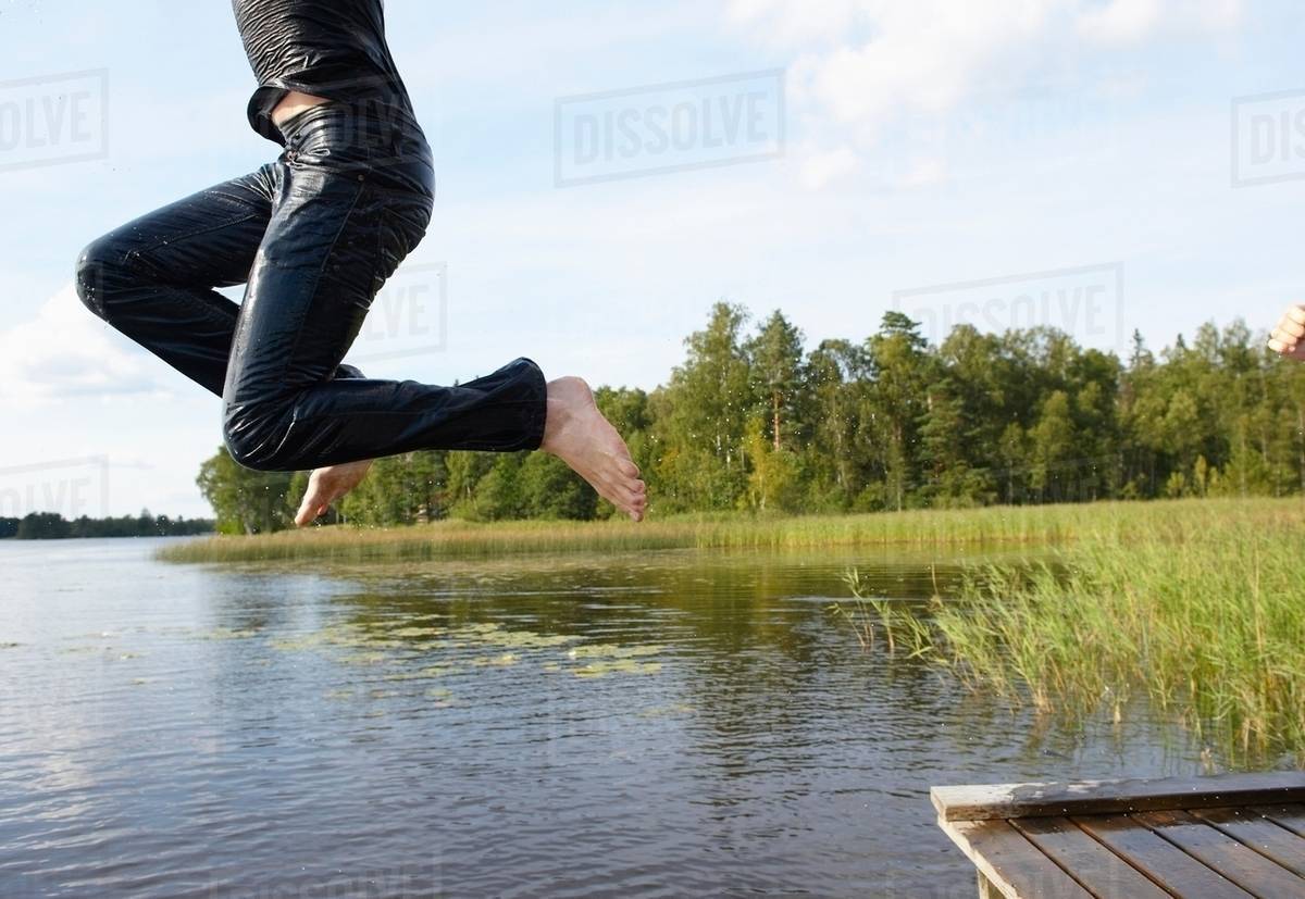 Man jumping in the lake with his clothes - Stock Photo - Dissolve