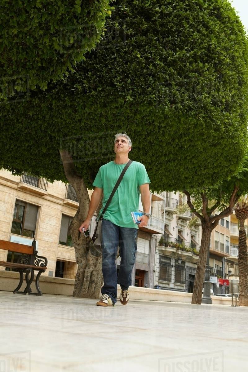 Man walking through city park - Royalty-free Stock Photo | Dissolve
