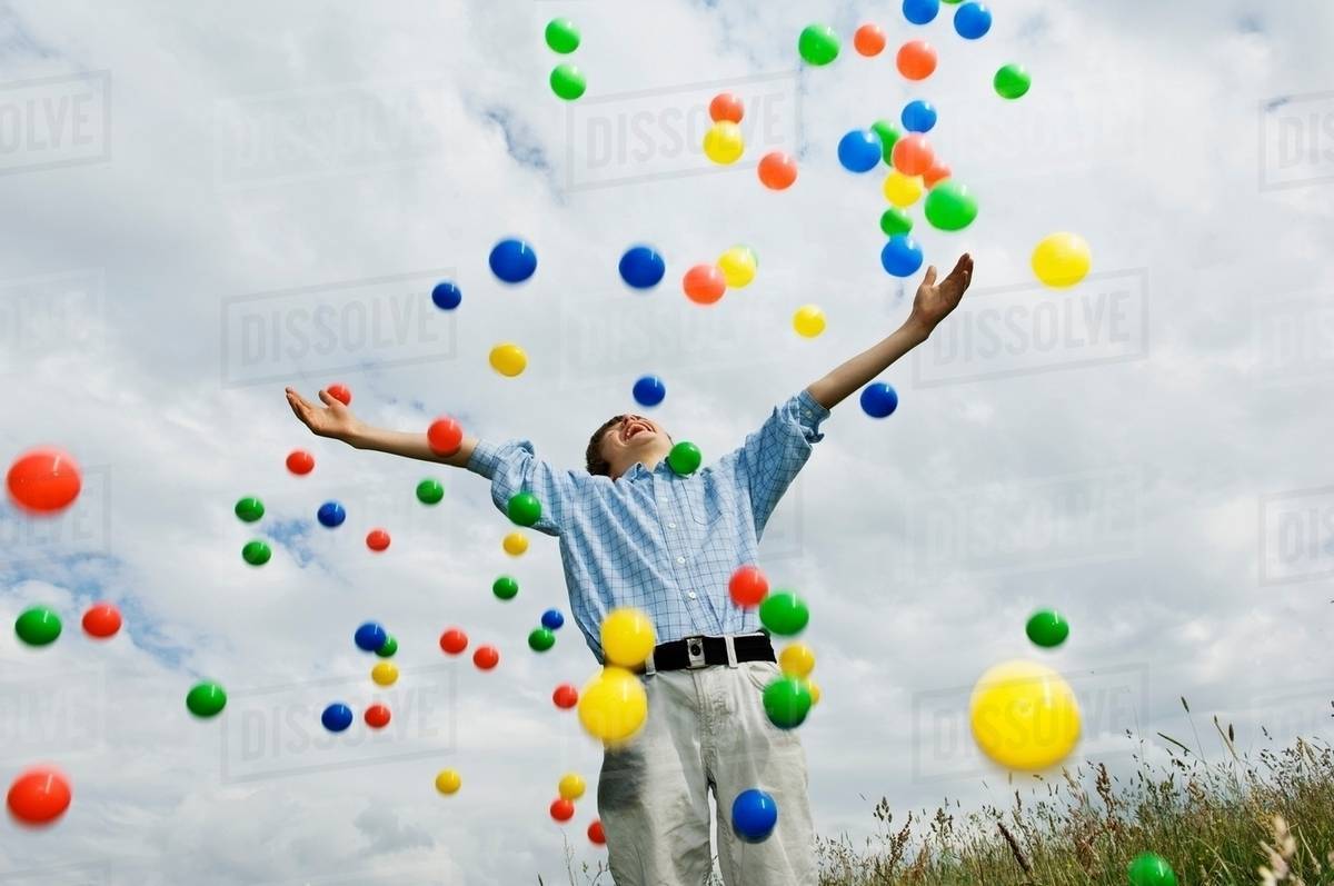 Young boy throwing colored balls - Stock Photo - Dissolve