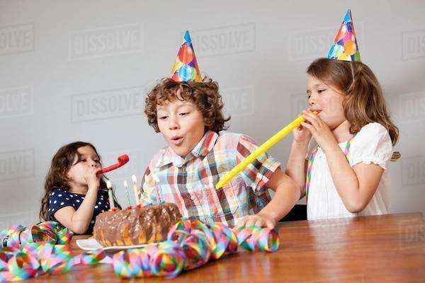 3 kids celebrating birthday party - Stock Photo - Dissolve