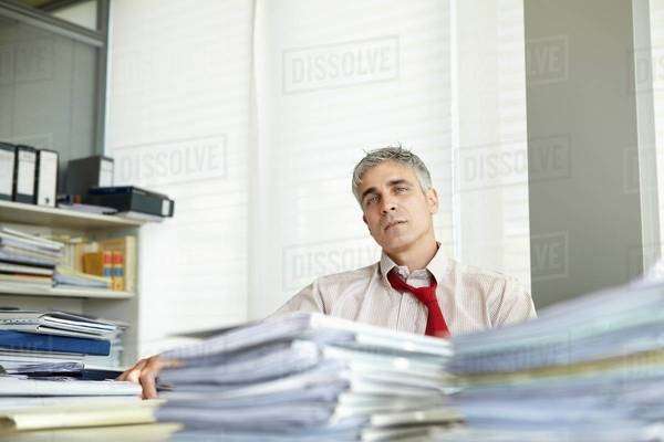 Man in office with pile of paperwork - Royalty-free Stock Photo | Dissolve
